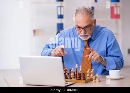 Old businessman playing chess in the office Stock Photo - Alamy