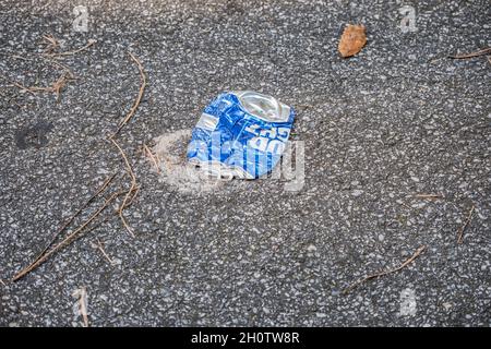 Crumpled a beer can on asphalt with spilled alcohol. Discarded broken ...