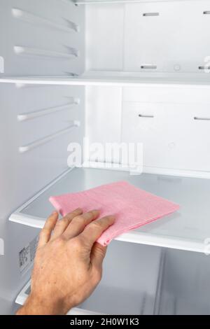 Hand cleaning refrigerator. Person washing refrigerator with rag ...