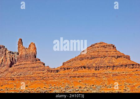 Red rock formations jutting out of the ground surrounded by shrubs ...