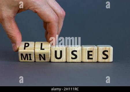 Pluses and minuses symbol. Businessman turns wooden cubes and changes ...