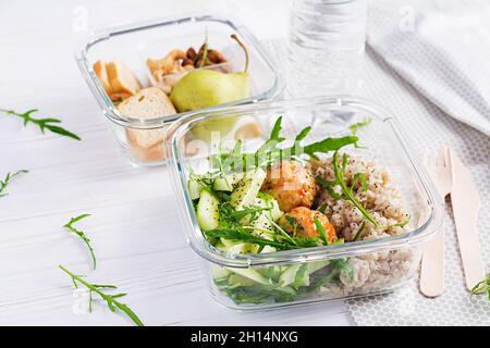 Lunch box filled with oatmeal, cucumber salad, and nuts, bread, pear on ...