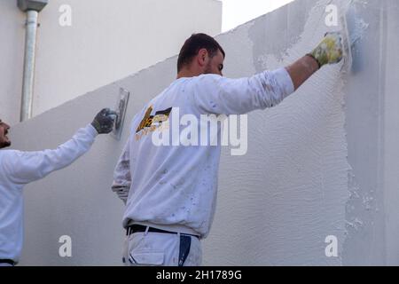 Plasterers plaster the facade of a new building Stock Photo - Alamy