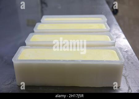 Worker taking fresh cheese from mould at modern factory, closeup ...