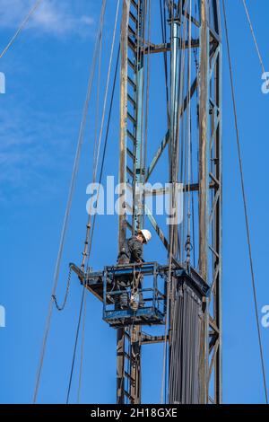 The derrickhand or derrickman working in the rod basket on the mast of ...