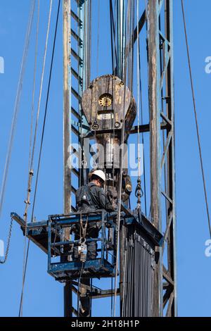 The derrickhand or derrickman working in the rod basket on the mast of ...