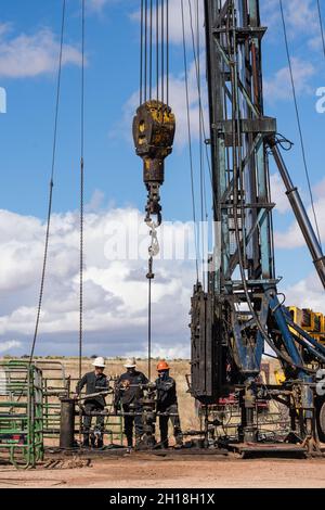 The well service crew on a workover rig works on an oil well to try to ...