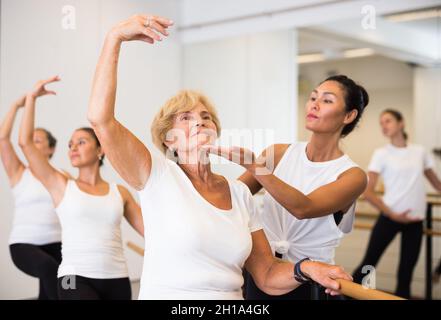 European woman performs an exercise near a ballet barre, where the ...