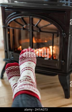 Woman warming up with feet on heater Stock Photo - Alamy