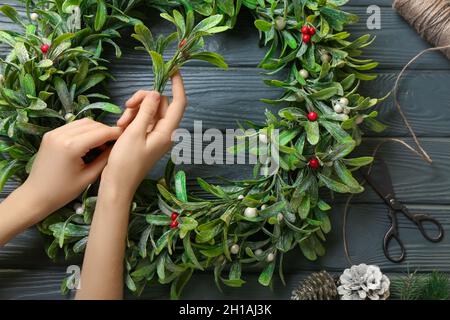 Woman decorated beautiful mistletoe wreath on wooden background Stock ...