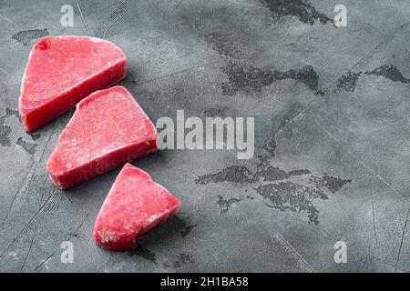 Frozen tuna fish steaks set, on wooden tray, on white stone background ...