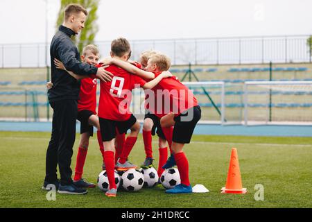 Coach giving instructions to children football team players during ...