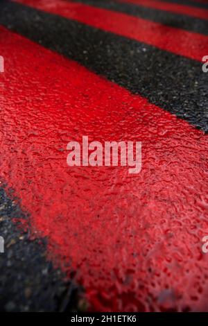 Wet red pavement and safety markings in a slippery area Stock Photo - Alamy