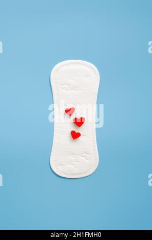 Blood, feminine hygiene pad with red heart on pink background. First ...