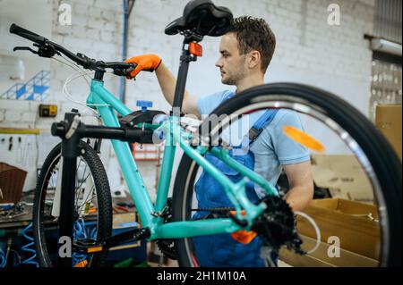 Bicycle factory, worker holds mountain bike Stock Photo - Alamy