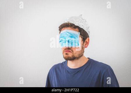 Young angry man with aluminum cap and face mask over the eyes is ...