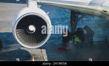 Ground service crew repairing and preparing airplane for flight in ...