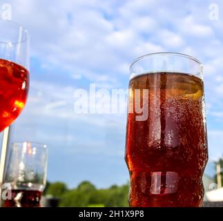 Refreshing orange summer cocktails with cola and ice against a blue sky ...