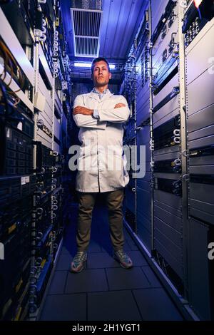 Calm system administrator standing in server room Stock Photo - Alamy