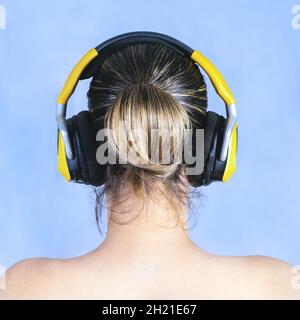 Woman with headphones standing on blue background Stock Photo - Alamy