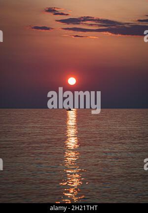 A vertical shot of a breathtaking sunset at the beach on a cloudy day ...