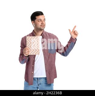 Young man with book and earphones pointing at something on color ...