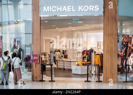 Shoppers stand outside the American clothing fashion store brand Michael Kors MK logo and store at Tung Chung district in Hong Kong Stock Photo Alamy
