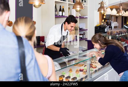 Visitors are choosing delicious cakes from showcase Stock Photo - Alamy