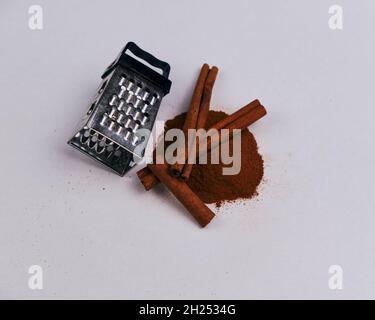 Cinnamon sticks and grater on white background Stock Photo - Alamy
