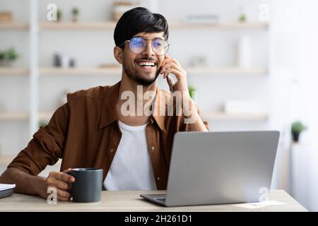 Happy arabic man freelancer working from home, using laptop Stock Photo ...