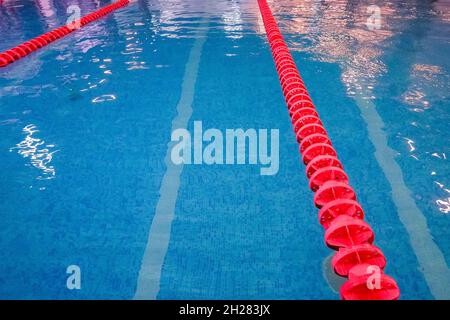 An empty sports pool with a red dividing path. Blue water in the ...