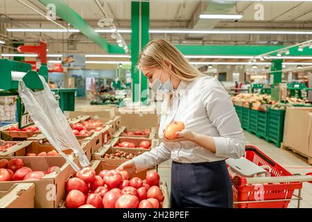 Smiling young woman choosing tomatoes in grocery store Stock Photo - Alamy