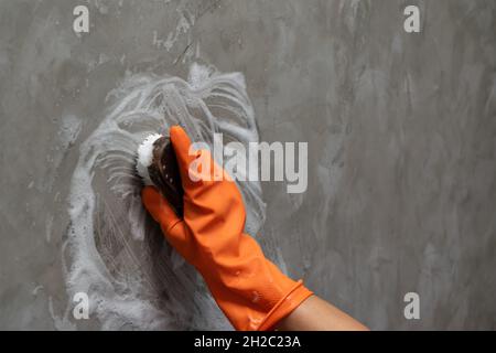 Professional cleaner wearing orange protective gloves sanitizing white ...