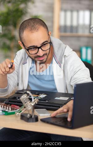 Technician repairing broken laptop notebook computer with screwdriver ...