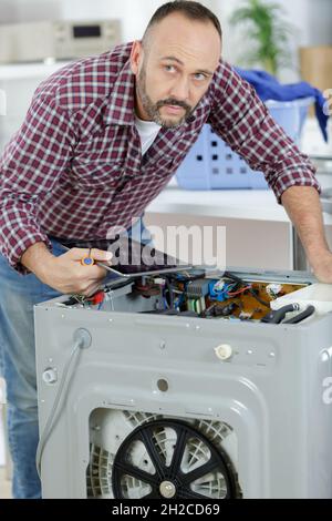 working man plumber repairs a washing machine in laundry Stock Photo ...