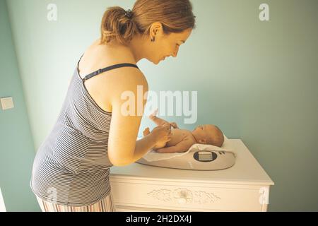 Mother weighs her newborn baby at home scales Stock Photo - Alamy