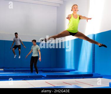 Female gymnast practicing middle split on trampoline Stock Photo - Alamy