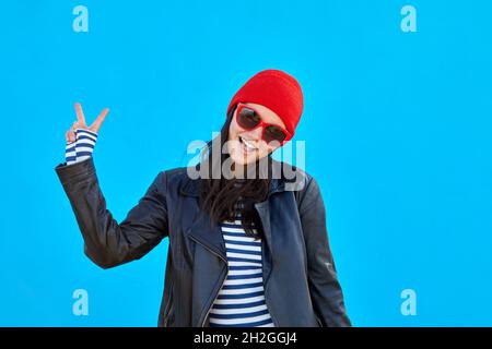 Delighted female millennial in trendy outfit standing near wall and ...