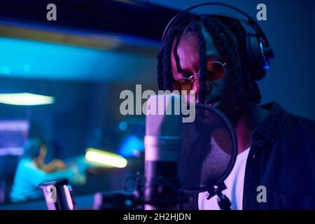 Young man in headphones, with microphone and mobile phone singing on ...