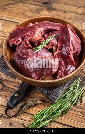 Raw sliced Beef or veal heart in a wooden tray with thyme. White wooden ...