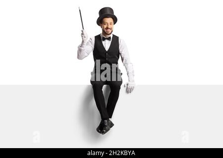 Magician sitting on a blank panel and smiling at camera isolated on ...