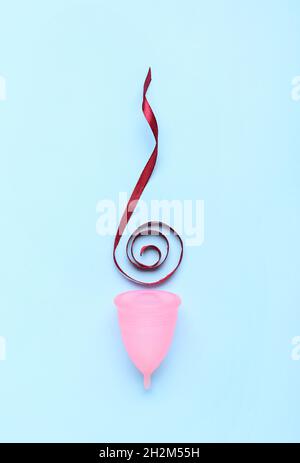 Menstrual cup and ribbon on color background Stock Photo - Alamy