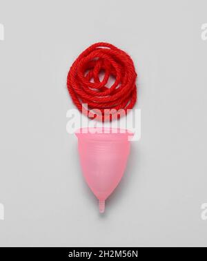 Menstrual cup and thread on color background Stock Photo - Alamy