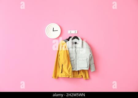 Stylish jackets and clock hanging on pink wall in hallway Stock Photo ...