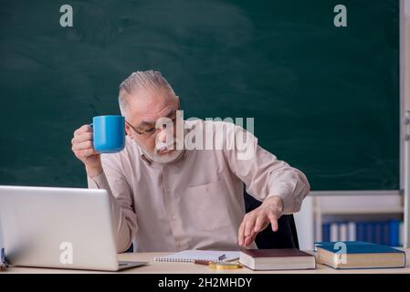 Old teacher drinking coffee in the classroom Stock Photo - Alamy