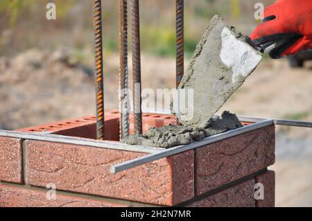 Bricklayer Worker Installing Red Clinker Blocks around Iron Bar and ...