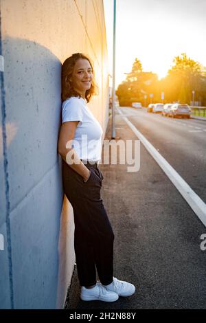Woman leaning on wall during sunny day Stock Photo - Alamy