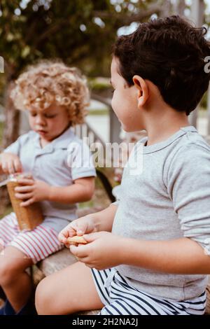 Cute children eating biscuits on sofa Stock Photo - Alamy