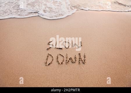 slow down, mindfulness concept written on sand Stock Photo - Alamy