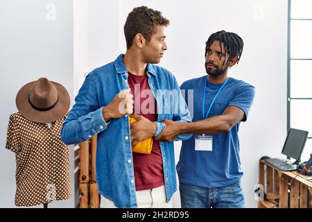 Two men shopkeeper and customer thief stealing clothes at clothing ...